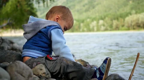 child throwing stones into the river | Stock Video | Pond5
