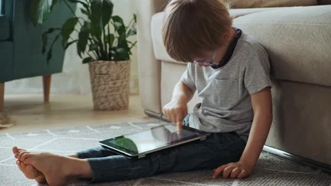 Child using tablet sitting on the floor ... | Stock Video | Pond5