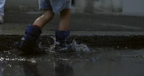 Child walking in water puddle in sidewal... | Stock Video | Pond5