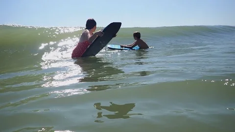 Children bodyboarding in ocean waves at ... | Stock Video | Pond5