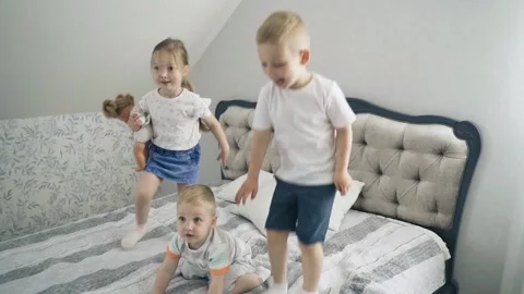 Children joyfully jump on the bed, play. | Stock Video | Pond5