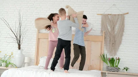 Children joyfully jump on the bed, play ... | Stock Video | Pond5