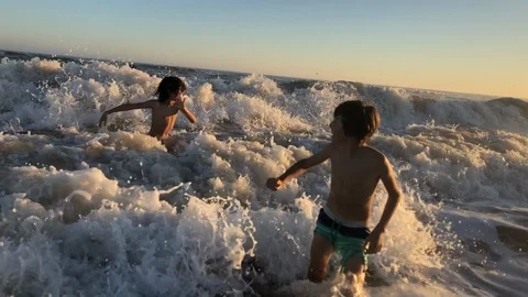 Children playing with beach waves | Stock Video | Pond5