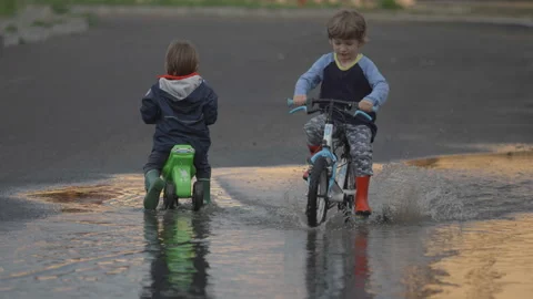 Children riding bike in a puddle, happy ... | Stock Video | Pond5