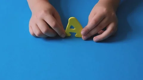 The child's hands wave the letter A. Yel... | Stock Video | Pond5