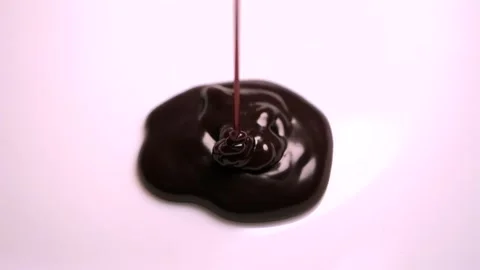Chocolate syrup dripping onto a white pl... | Stock Video | Pond5