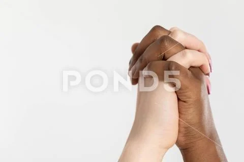 Photograph: Clasped hands of two girls in love raised up. Handshake ...