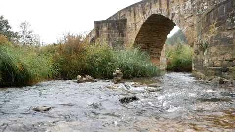 clear river flows under a medieval bridg... | Stock Video | Pond5