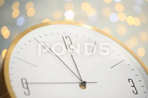 Clock showing five minutes until midnight on blurred background ...