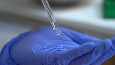 Close-up dripping a liquid into a gloved... | Stock Video | Pond5