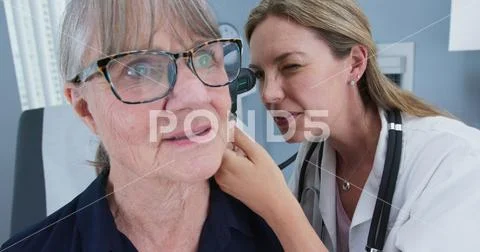 Photograph: Close up of female doctor using otoscope to look into older ...