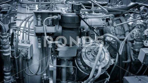 A close-up of a gas turbine engine with many wires and tubes. The ...