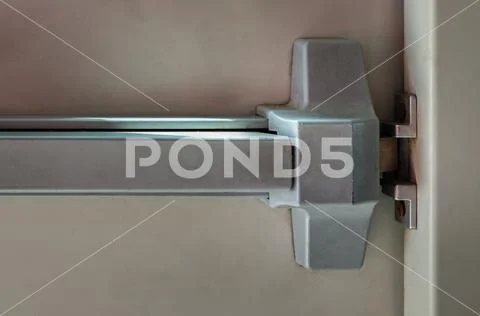 Close-up of latch and door handle of emergency exit. Push bar and rail ...