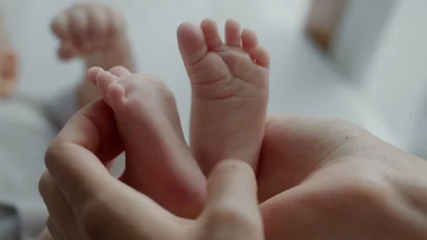 Close-up loving mother holds tiny feet o... | Stock Video | Pond5