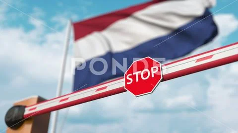 Closed boom barrier with stop sign against the Dutch flag. Restricted ...