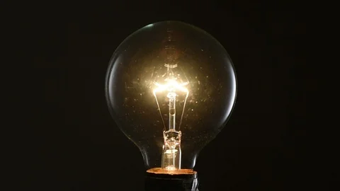 Closeup flashing light bulb on black bac... | Stock Video | Pond5