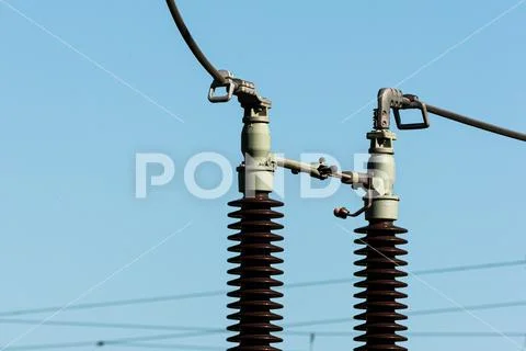 Closeup of two long rod insulators on a pale clear sky background Stock ...
