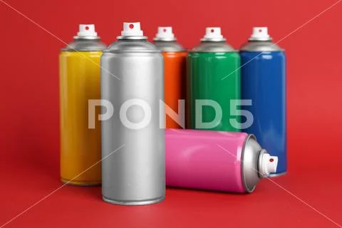 Photograph: Colorful cans of spray paints on red background #224206072