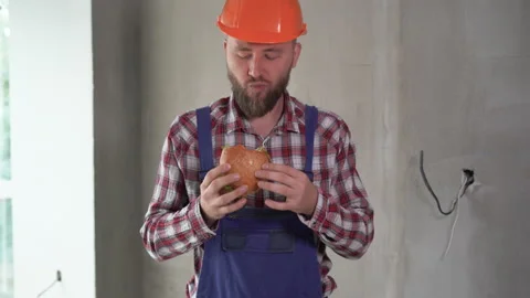 Construction worker in helmet eating bur... | Stock Video | Pond5