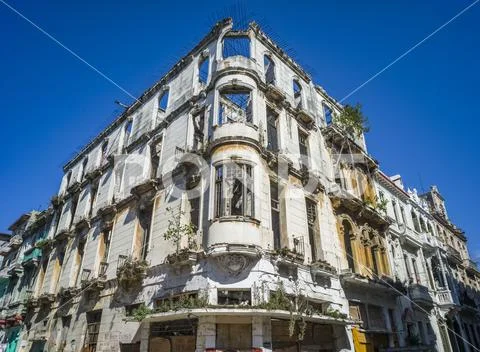 Photograph: Corner of an old abandoned building with broken windows and rebar sticking out ...