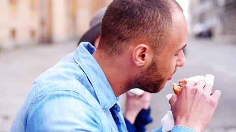 Couple sitting at curb and eating hambur... | Stock Video | Pond5