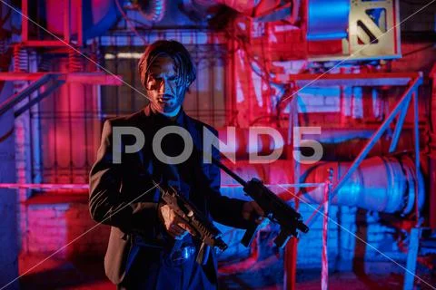 Photograph: Courageous action hero with automatic guns in an industrial ...