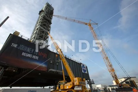 Cranes and rigging are being used to lift up the Core Stage Forward ...