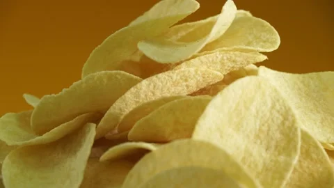 Crispy potato chips rotating on yellow b... | Stock Video | Pond5