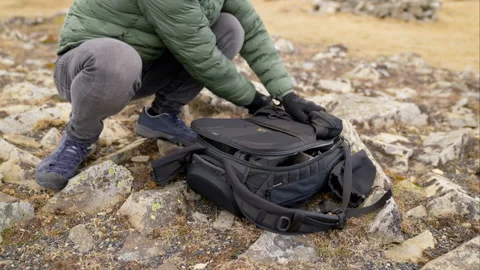 Crouching man opening backpack for camer... | Stock Video | Pond5