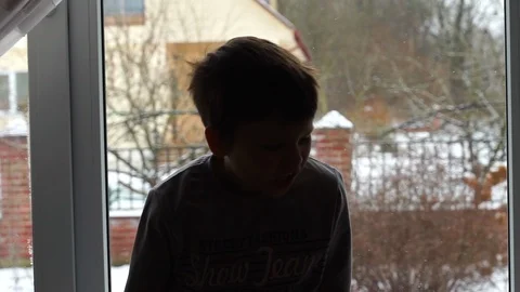 crying kid sitting on the window sill an... | Stock Video | Pond5