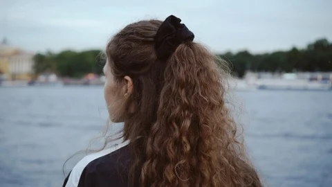 Curly cute girl stands backwards, turns ... | Stock Video | Pond5
