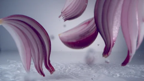 Cut red onion falling on water surface. ... | Stock Video | Pond5