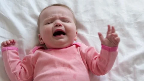 Cute baby is crying, laying on a white b... | Stock Video | Pond5