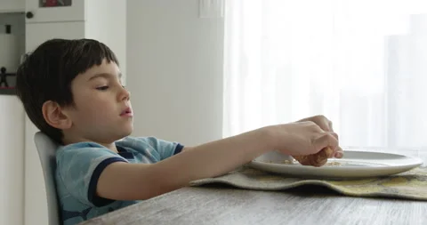 Cute boy nibbles bread in front of his l... | Stock Video | Pond5