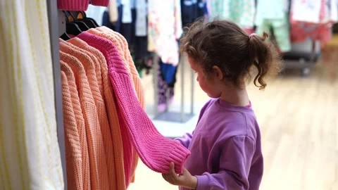 Cute child girl chooses clothes in shop ... | Stock Video | Pond5