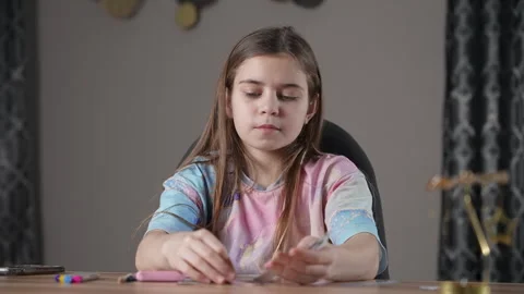 Cute girl sitting at table, thinking whi... | Stock Video | Pond5