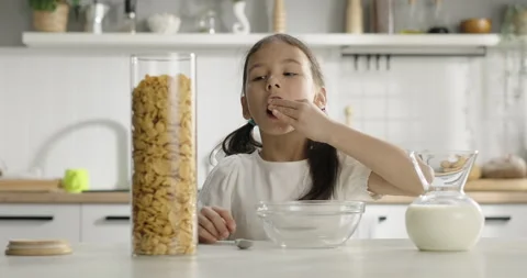 Cute kid girl tastes corn flakes. Little... | Stock Video | Pond5