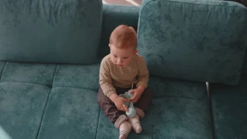 Cute little child boy sitting on sofa wi... | Stock Video | Pond5