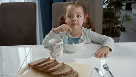 Cute, little girl eating flakes with mil... | Stock Video | Pond5