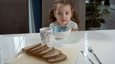 Cute, little girl eating flakes with mil... | Stock Video | Pond5
