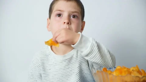 Cute preschool boy eats potato chips, un... | Stock Video | Pond5