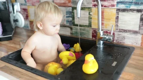 Cute smiling baby taking bath in kitchen... | Stock Video | Pond5