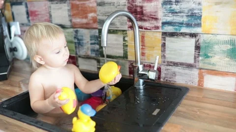 Cute smiling baby taking bath in kitchen... | Stock Video | Pond5