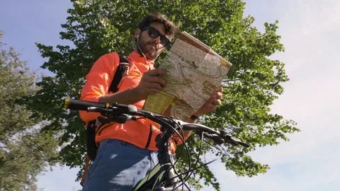 Cyclist with bike reads map for directio... | Stock Video | Pond5