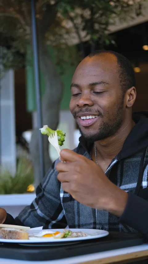 dark-skinned man eating broccoli for bre... | Stock Video | Pond5