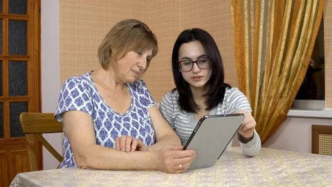 Daughter teaches mother how to use a tab... | Stock Video | Pond5