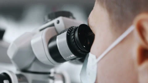 A dentist looks at a tooth under a micro... | Stock Video | Pond5