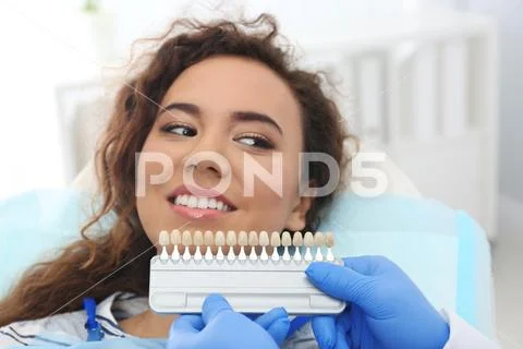 Dentist matching patient's teeth color with palette in office Stock ...