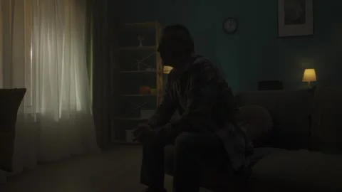 A devastated man sits in a room in the d... | Stock Video | Pond5