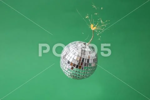 Disco bomb concept. Disco ball with a lit fuse, levitating on green ...